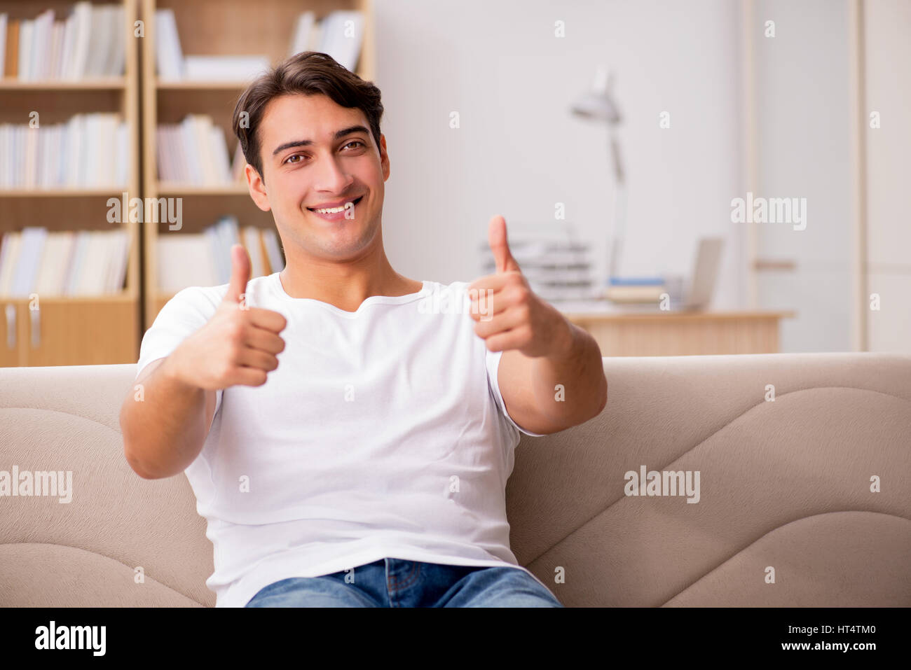 Young man relaxing sitting in couch sofa Stock Photo - Alamy
