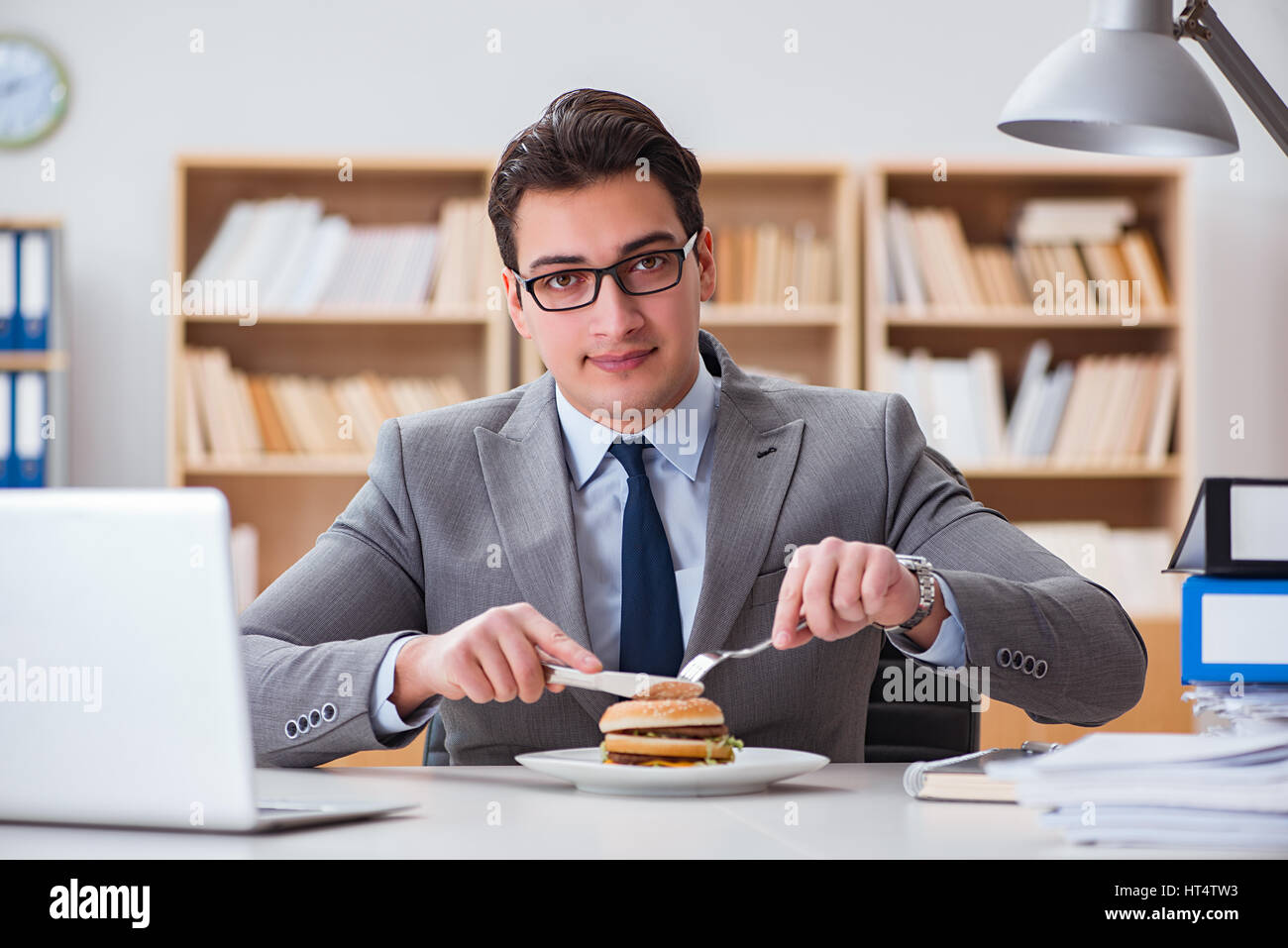 Hungry funny businessman eating junk food sandwich Stock Photo - Alamy