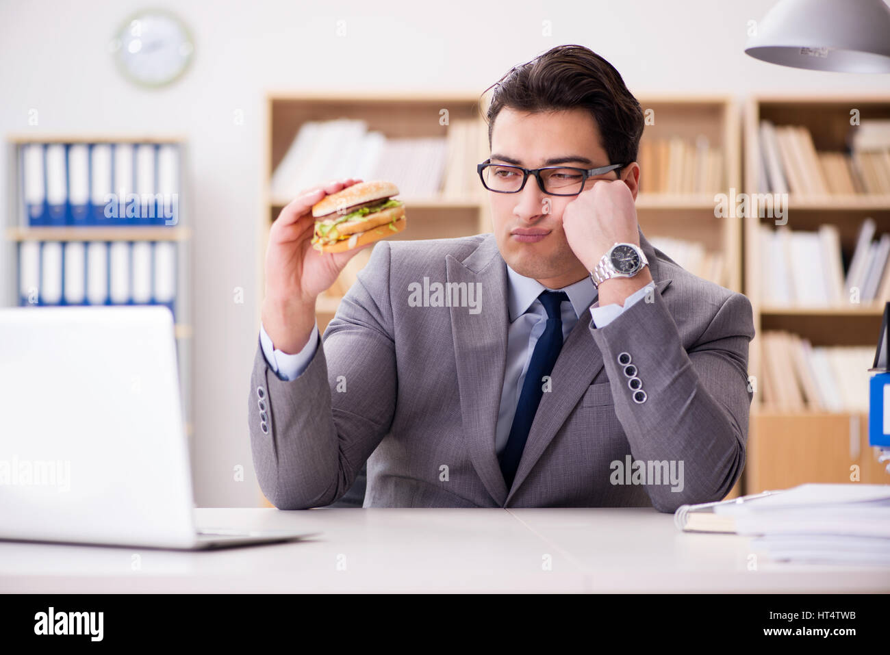 Hungry funny businessman eating junk food sandwich Stock Photo - Alamy