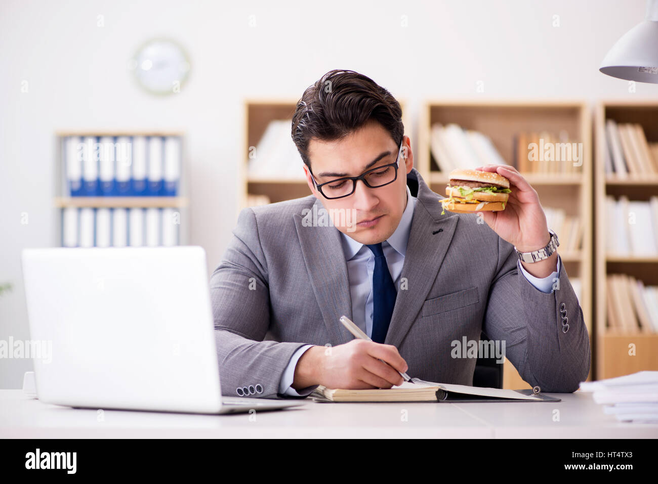 Hungry funny businessman eating junk food sandwich Stock Photo - Alamy