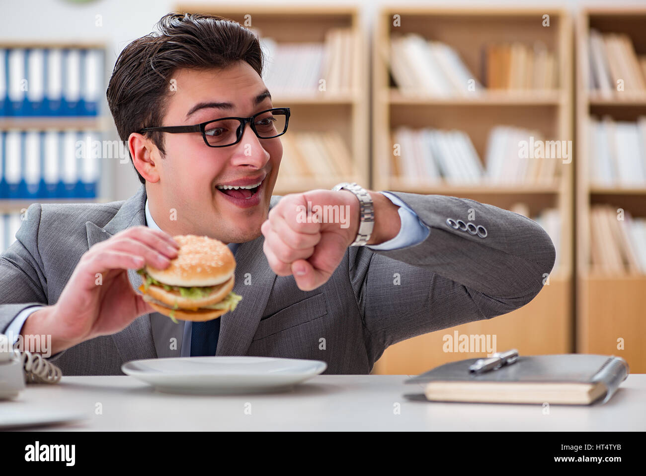 Hungry funny businessman eating junk food sandwich Stock Photo - Alamy