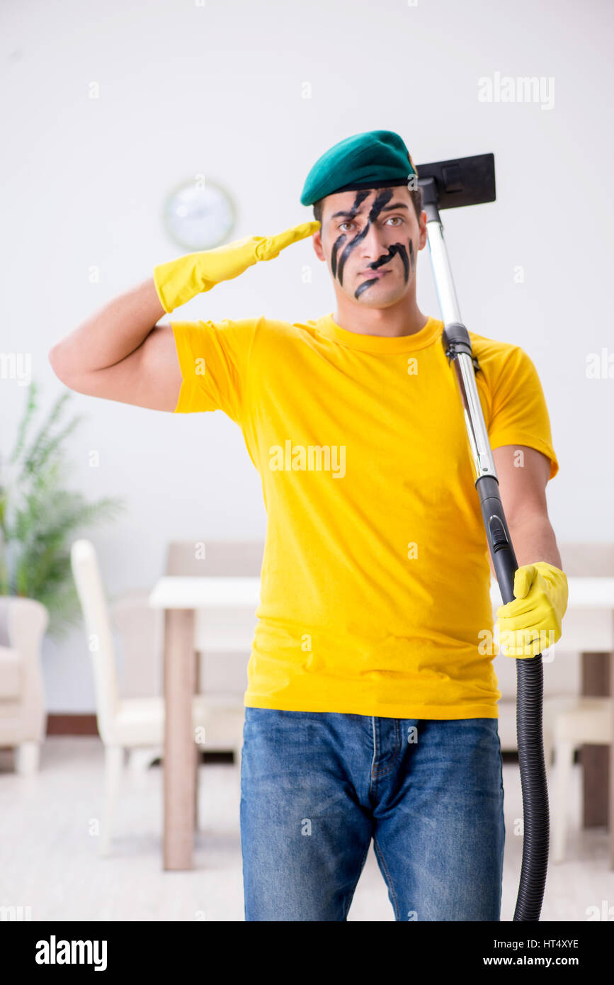 Funny man in military style cleaning the house Stock Photo - Alamy