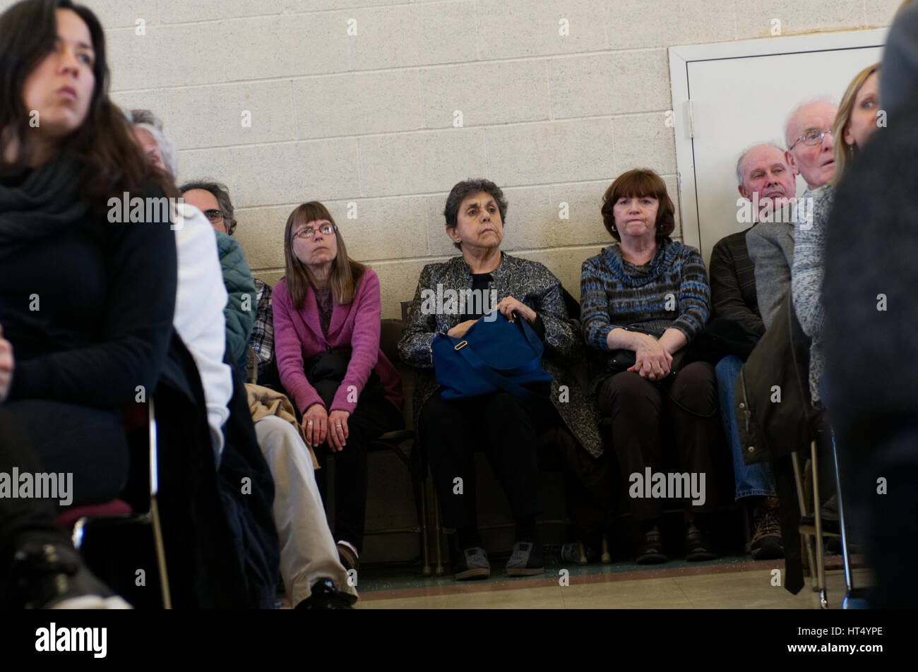 Community members listen as an elected representative reacts to ...