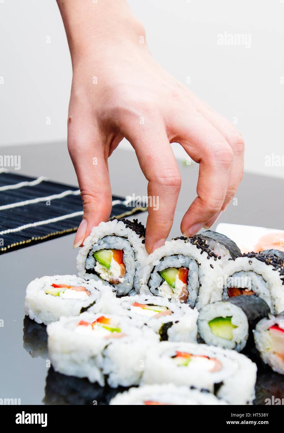 Hand holding sushi on black background Stock Photo - Alamy
