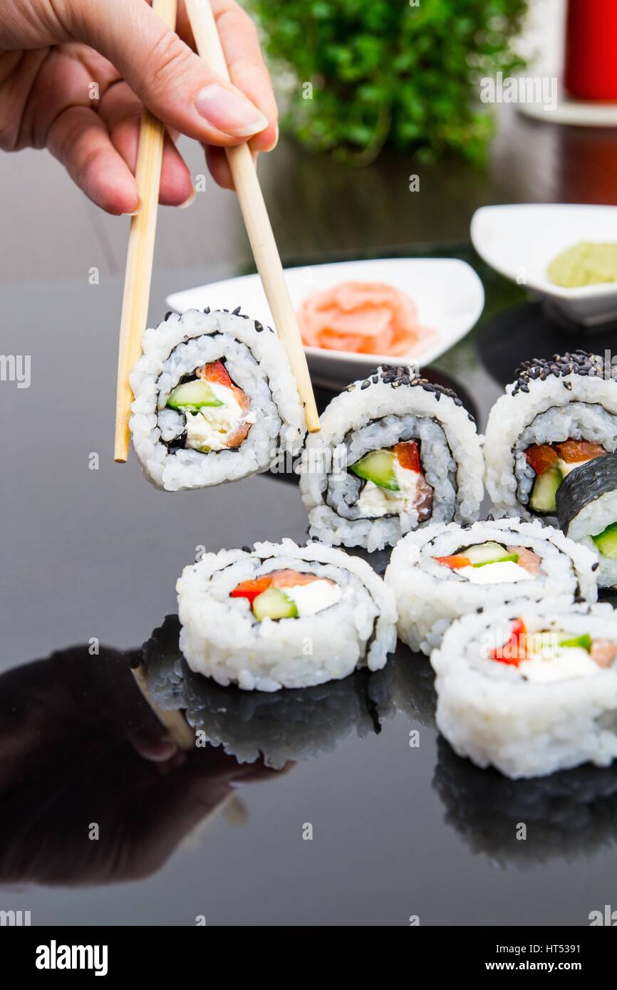 Hand holding stick with maki sushi set Stock Photo - Alamy