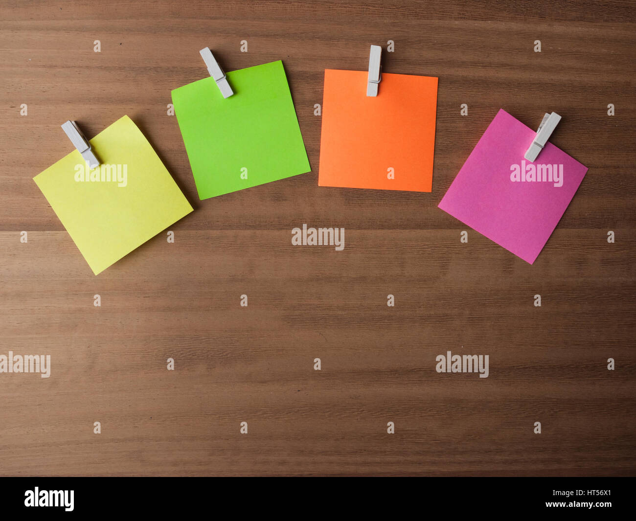 Four Post It notes displayed in an arc on small pegs, layed out on ...