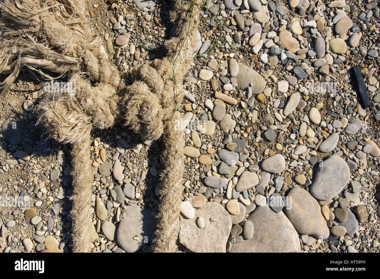 old worn battered marine rope on the pebble beach on a Sunny summer day ...