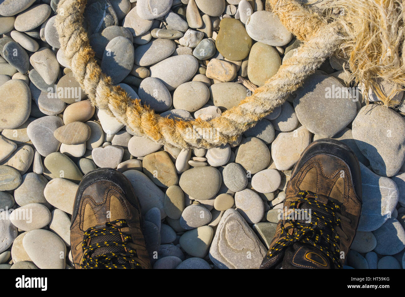 old worn battered marine rope on the pebble beach on a Sunny summer day ...