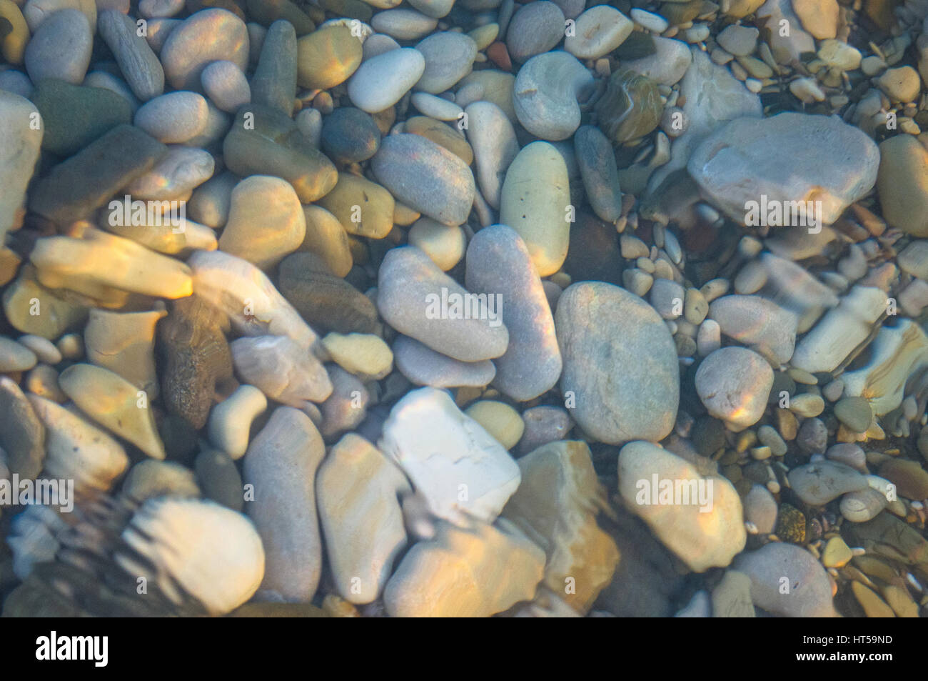 sea pebble beach with multicoloured stones, transparent waves with foam ...