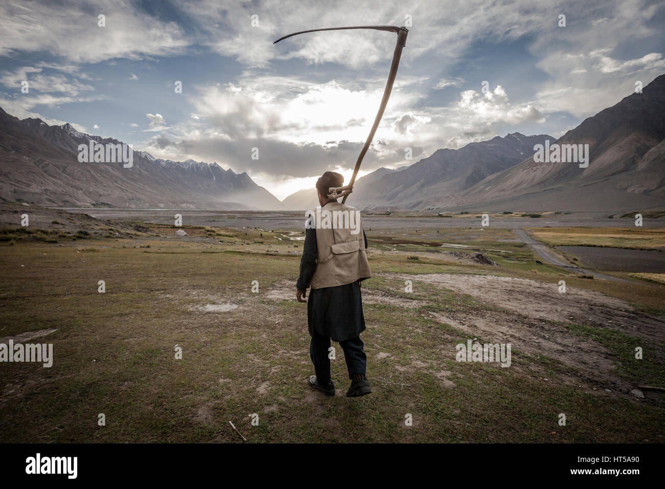 Afghanistan, Wakhan corridor, man with sickle in valley, walking in ...
