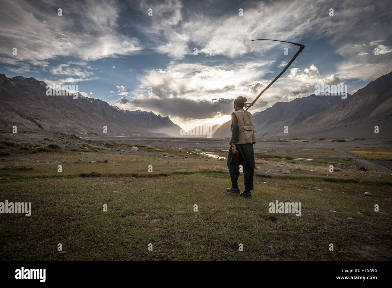 Afghanistan, Wakhan corridor, man with sickle in valley, walking in ...