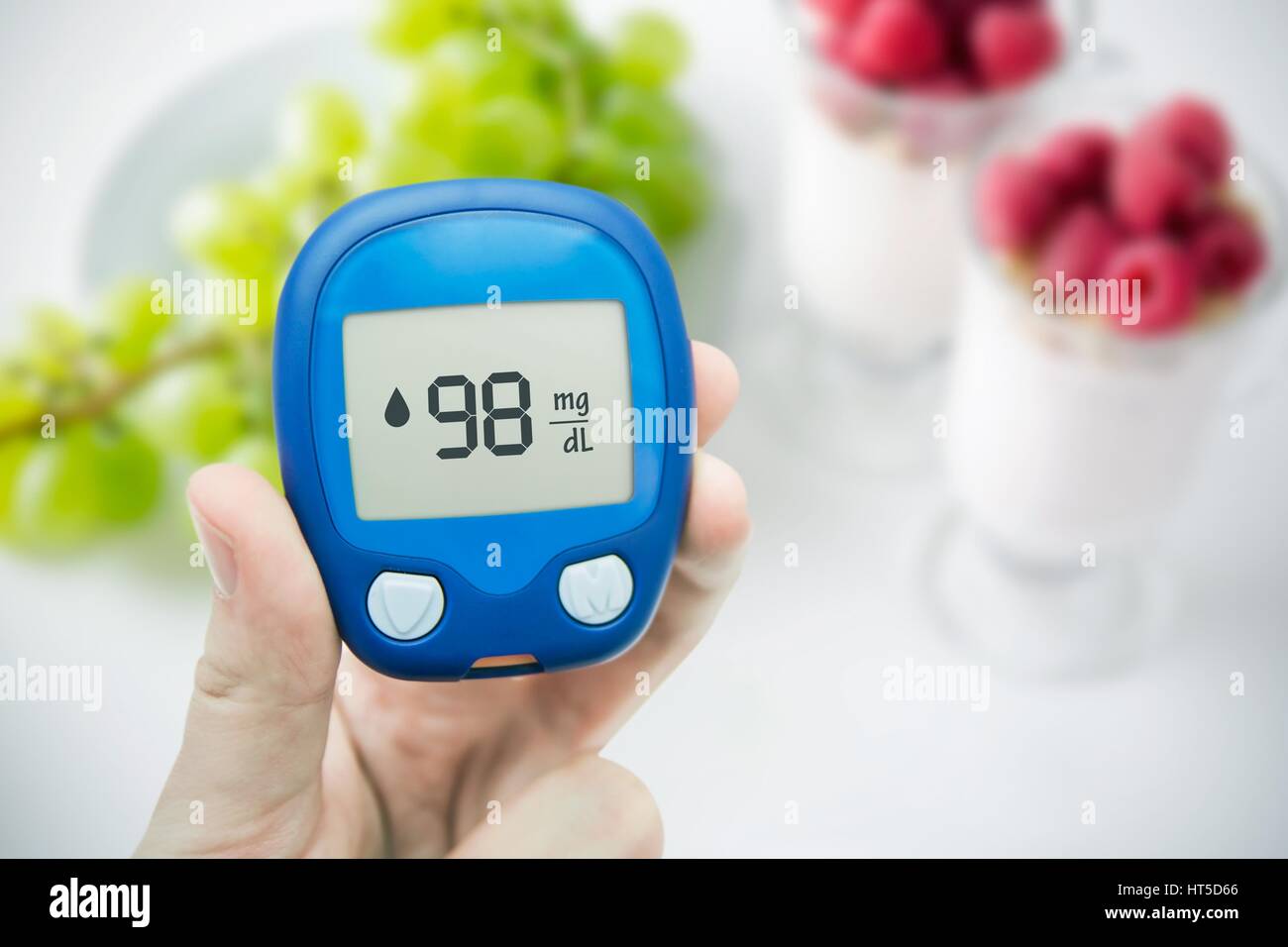 Hand holding meter. Diabetes doing glucose level test. Fruits in ...