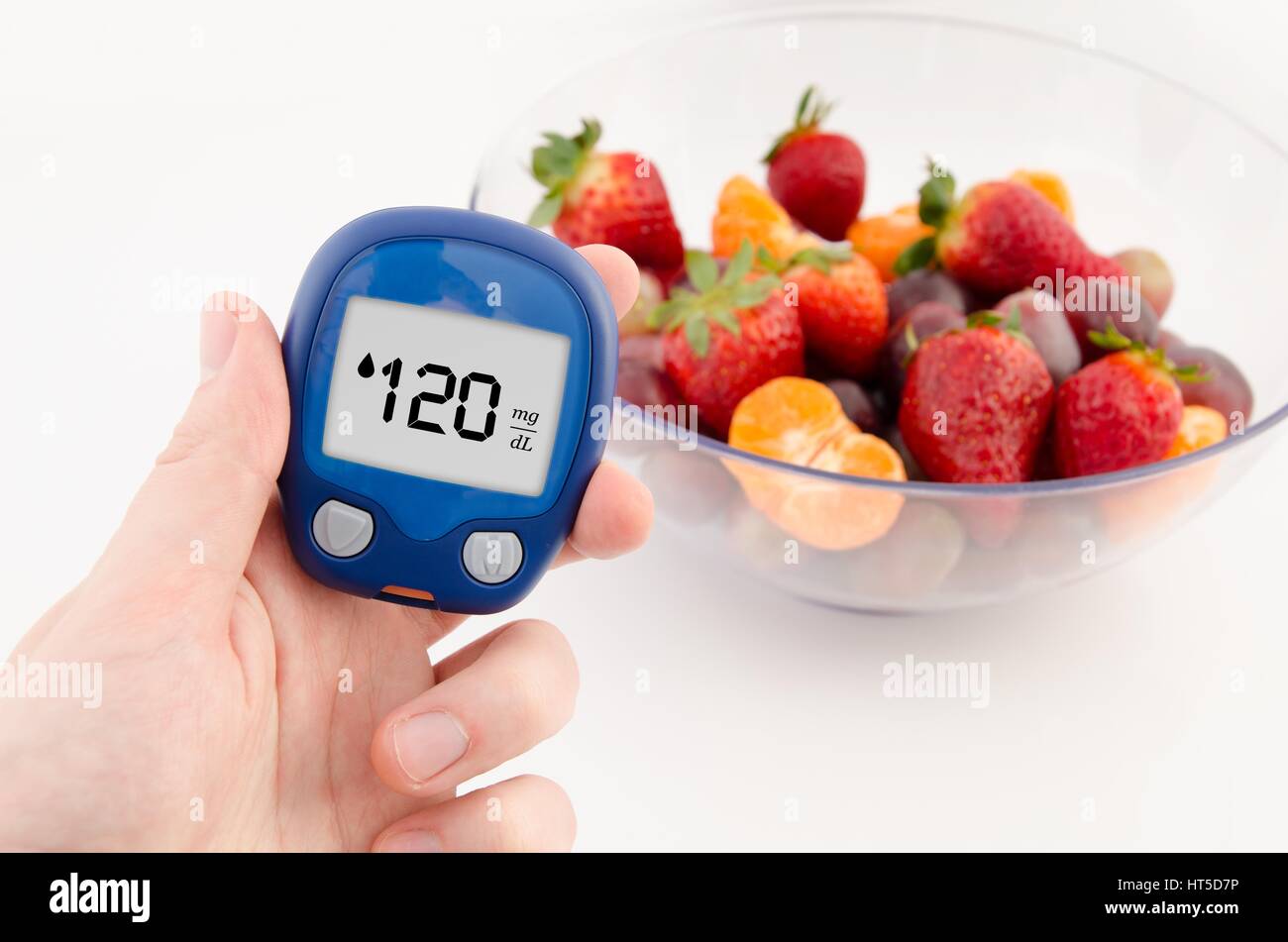 Hand holding meter. Diabetes doing glucose level test. Fruits in ...
