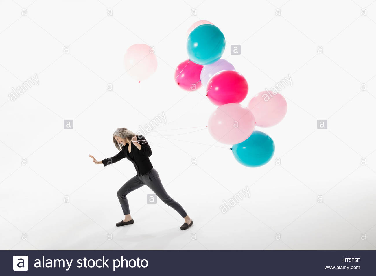 Woman pulling vibrant balloons against white background Stock Photo - Alamy