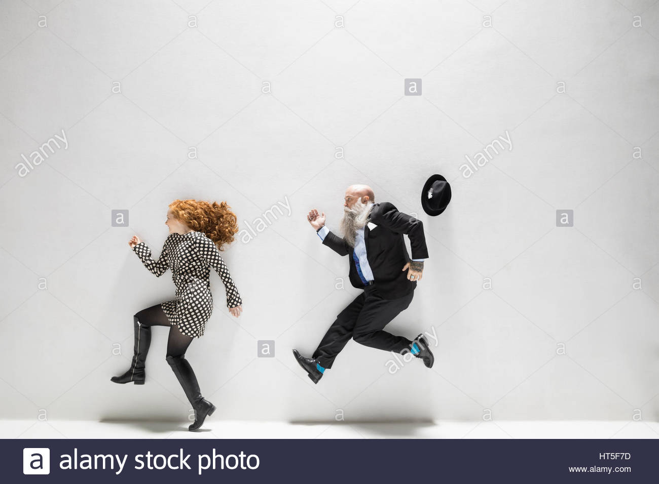 Businessman chasing businesswoman against white background Stock Photo ...