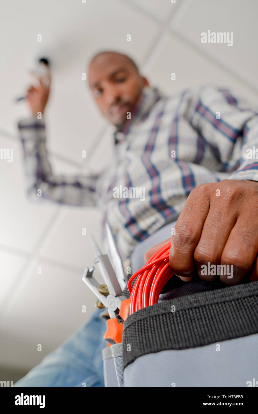 Builder working on ceiling, reaching into toolbelt Stock Photo - Alamy