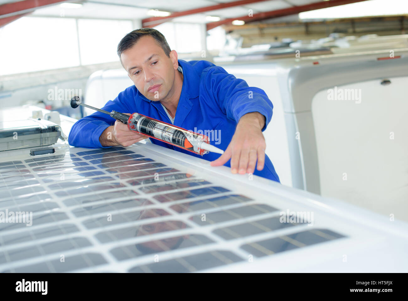 Man sealing around solar panel on roof of vehicle Stock Photo - Alamy