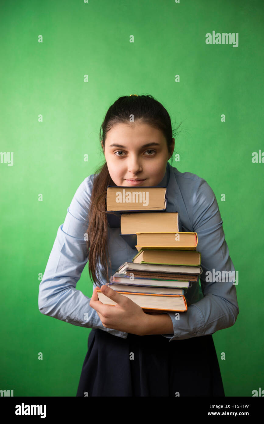 teen girl with long hair in the blue shirt holding a stack of books in ...