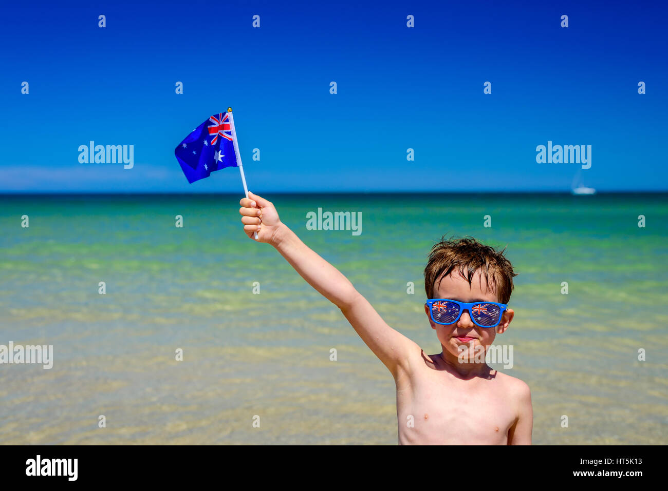 Cute smiling boy with Australian flag standing on the beach on ...