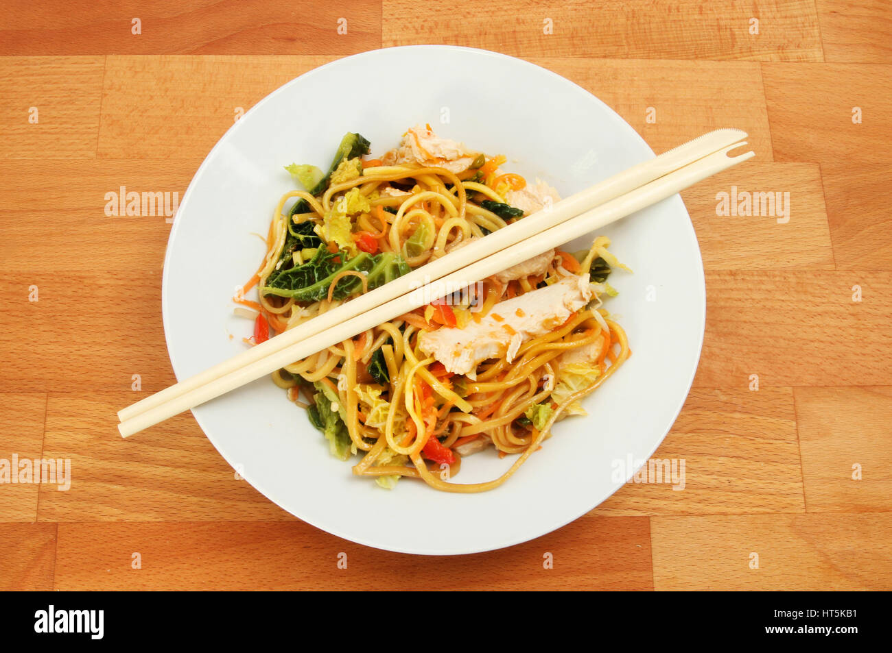 Chicken Chow Mein in a bowl with chopsticks on a wooden tabletop Stock ...