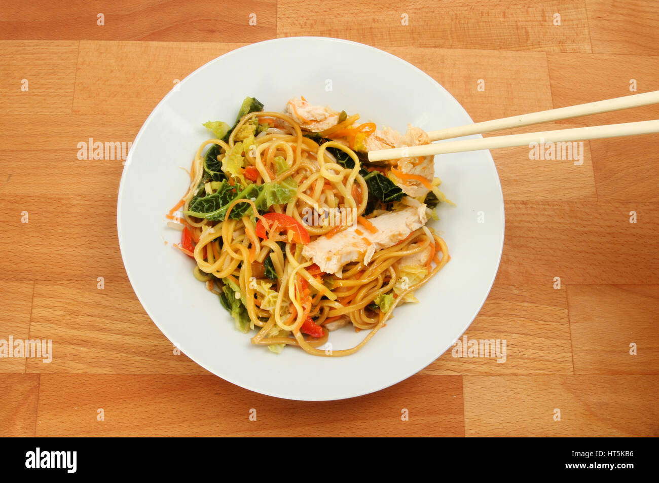 Chicken Chow Mein in a bowl with chopsticks on a wooden tabletop Stock ...