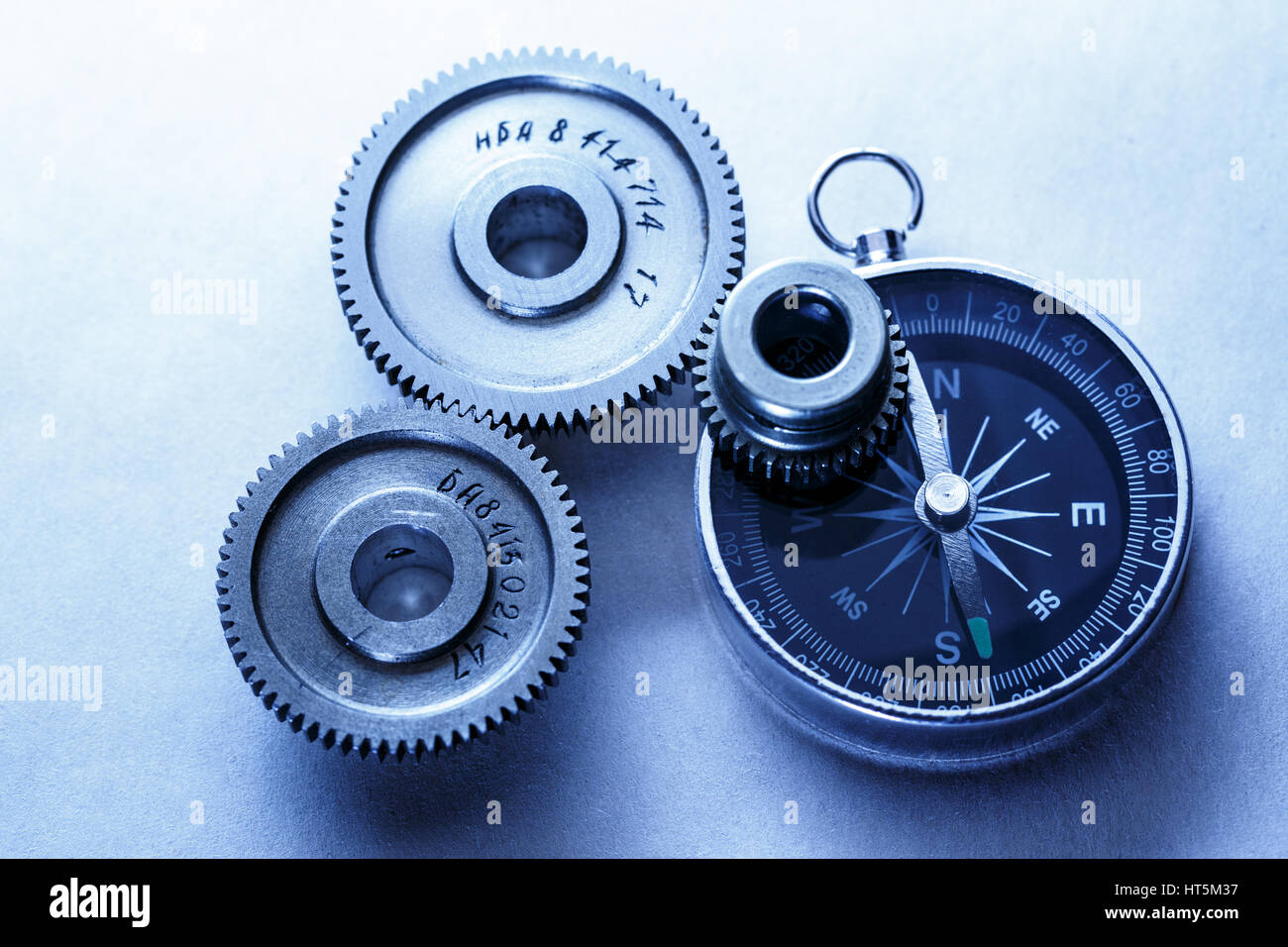 Three steel cogwheels with compass in closeup Stock Photo - Alamy