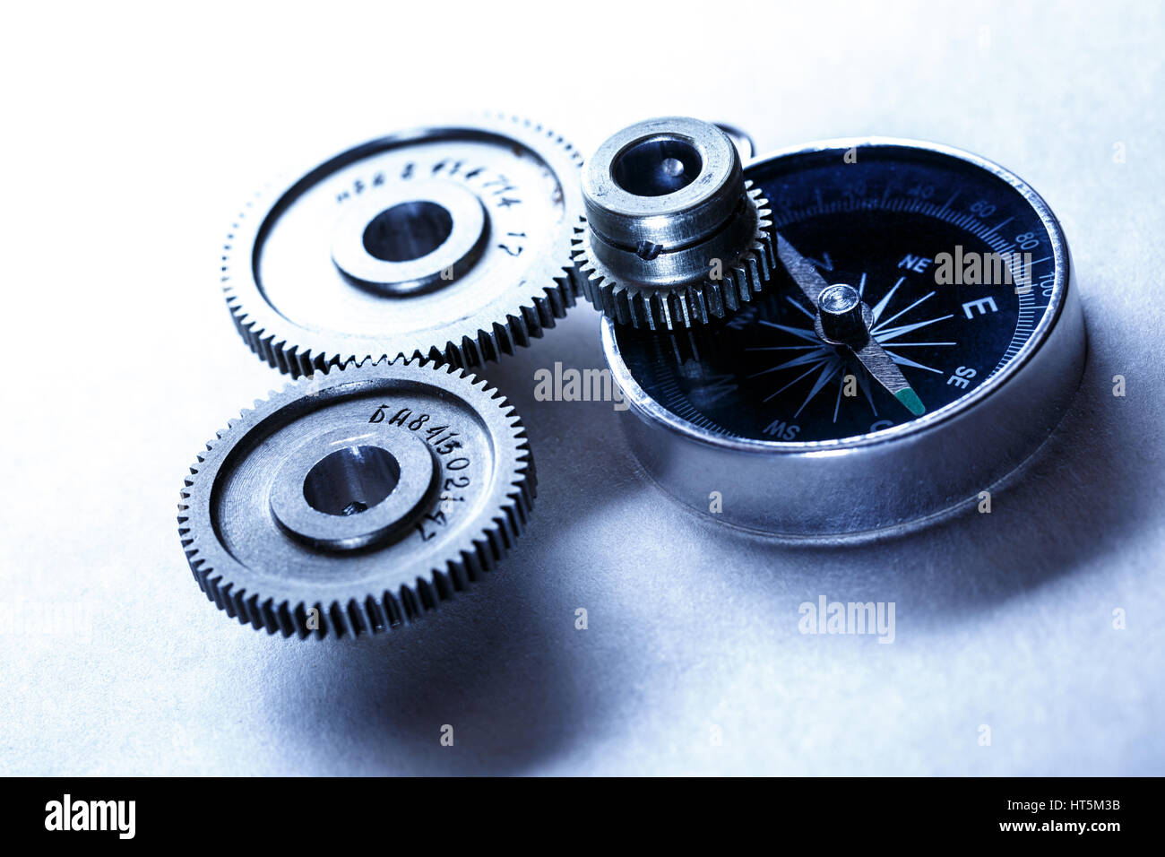 Three steel cogwheels with compass in closeup Stock Photo - Alamy