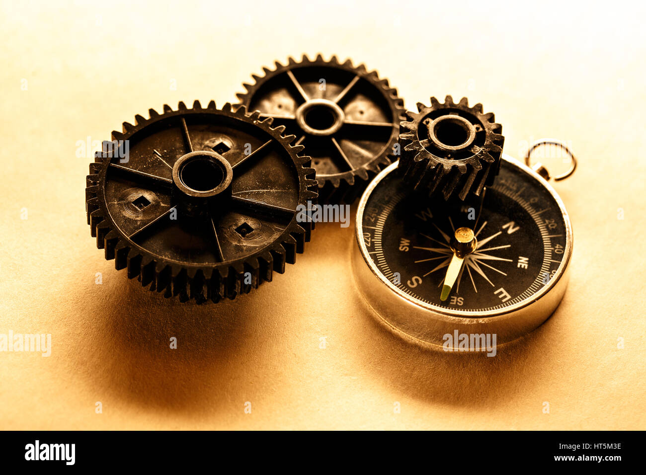 Three steel cogwheels with compass in closeup Stock Photo - Alamy