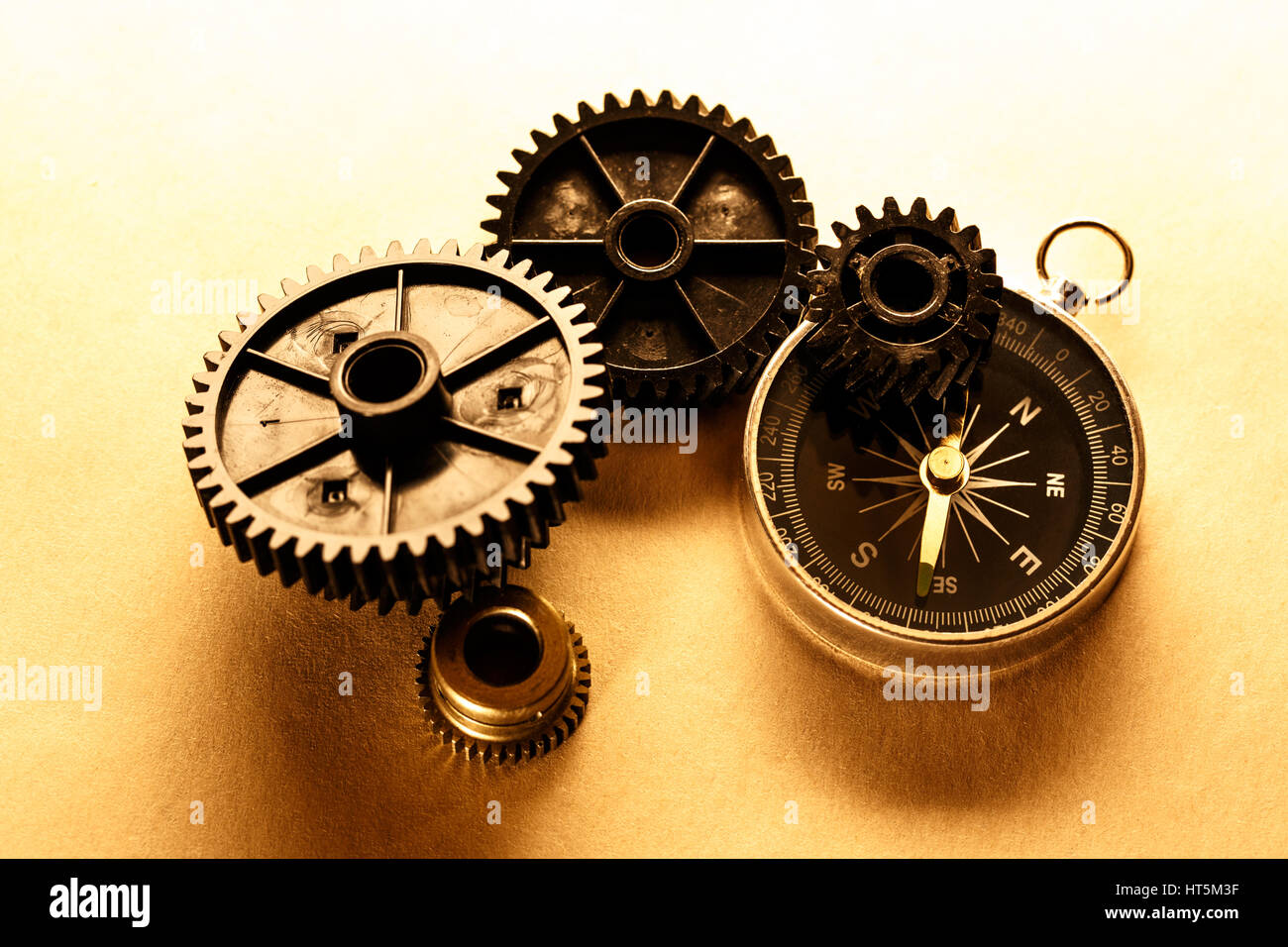 Three steel cogwheels with compass in closeup Stock Photo - Alamy