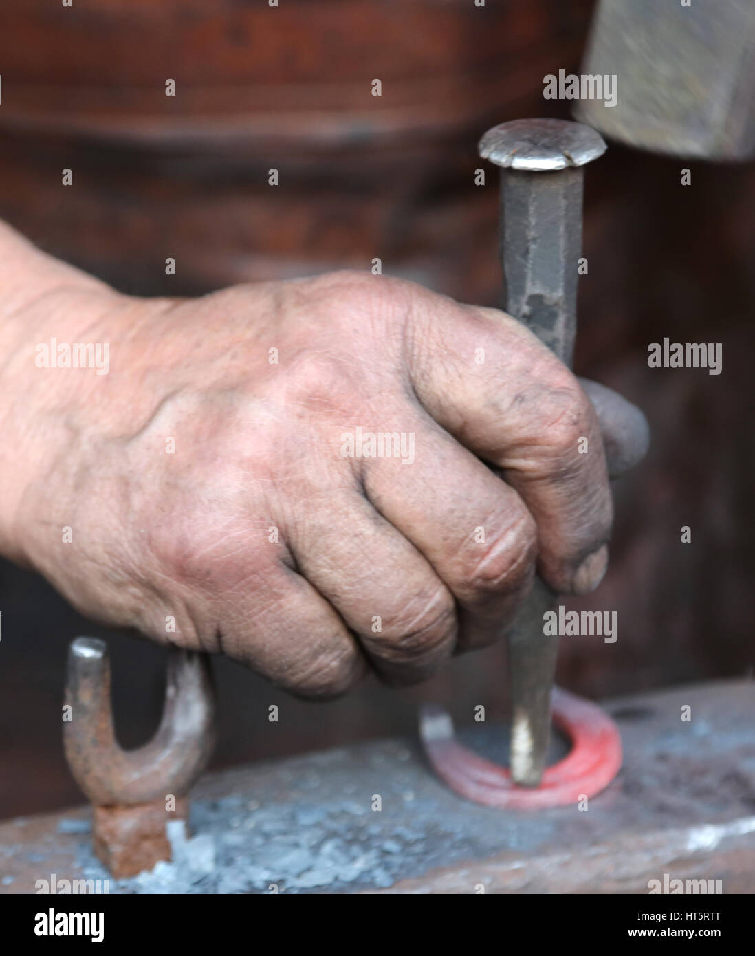 hand elder blacksmith who uses an iron awl over a large anvil Stock ...