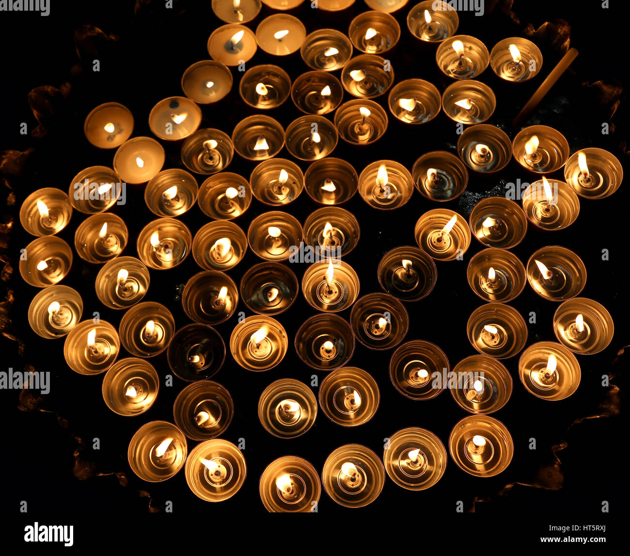 many candles lit with the warm flame during the religious ceremony ...