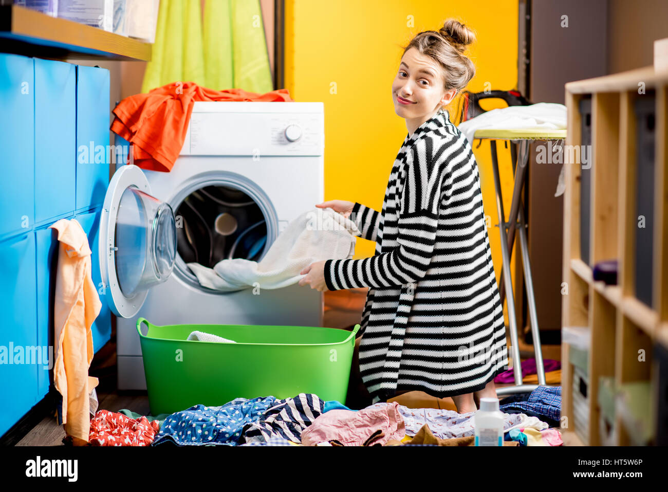 Young housewife loading clothes into the washing machine sitting on the ...