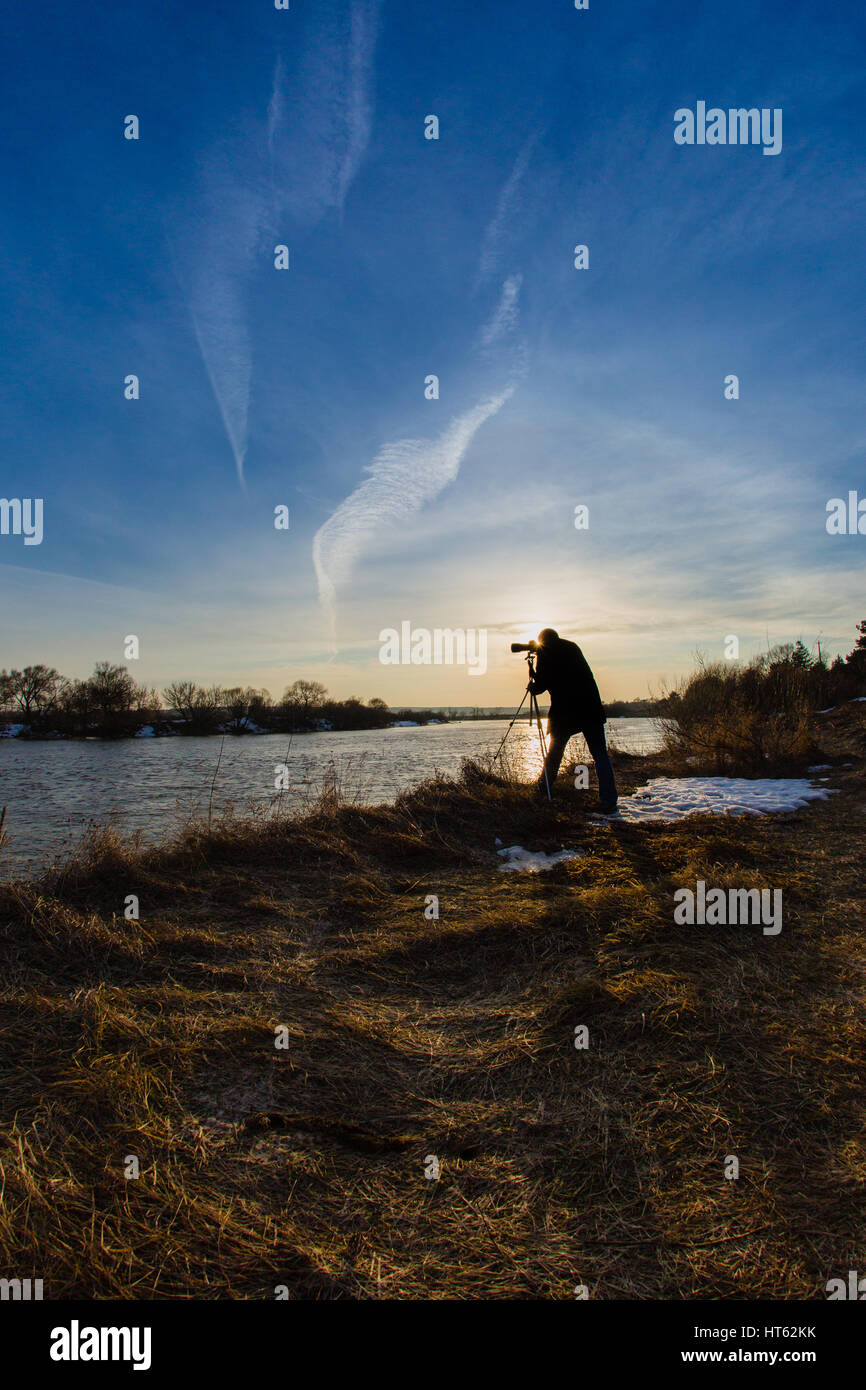 Professional photographer taking a photo flooding river at sunset Stock ...