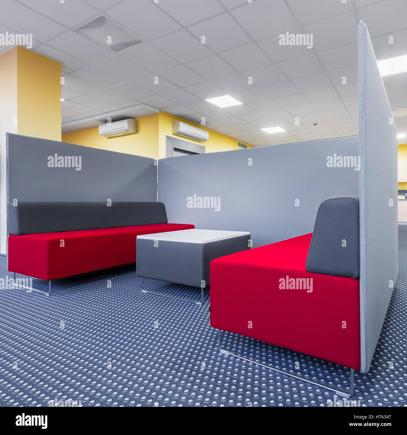 University lounge area with red sofa, table and grey partition Stock ...