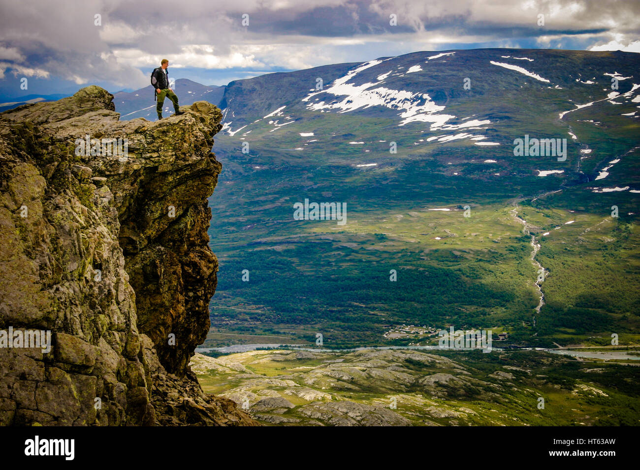 Man standing at edge of cliff at Mount Besseggen, Norway Stock Photo ...