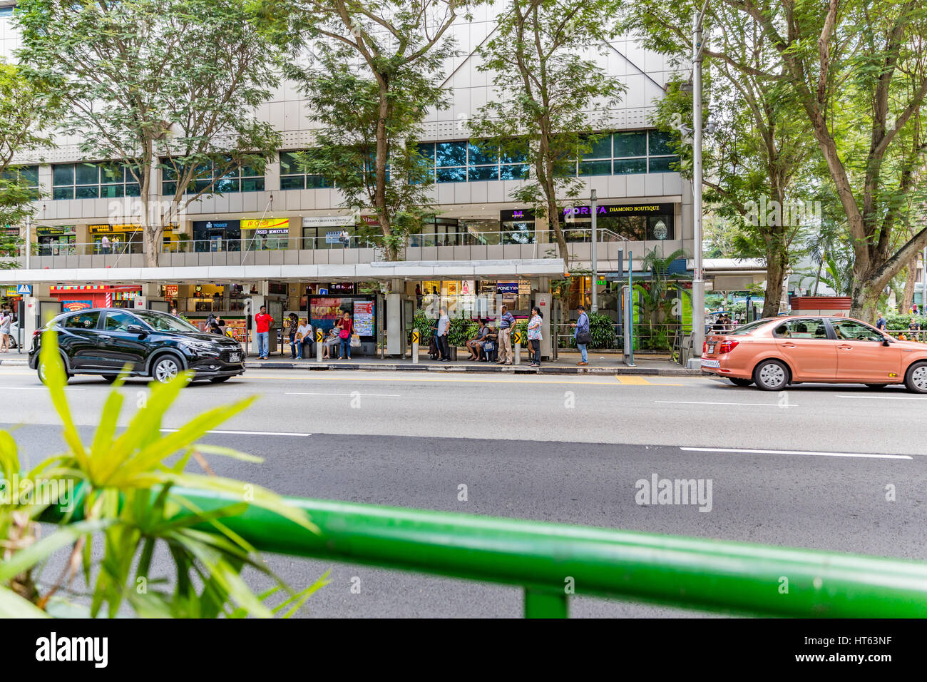 Cars pass pedestrians waiting in taxi queue in Orchard Road, Singapore ...