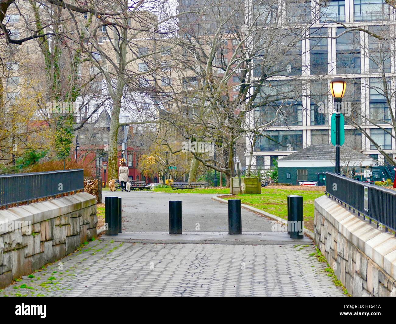 Trenchcoat-wearing woman walking two dogs in Carl Schurz Park on a ...