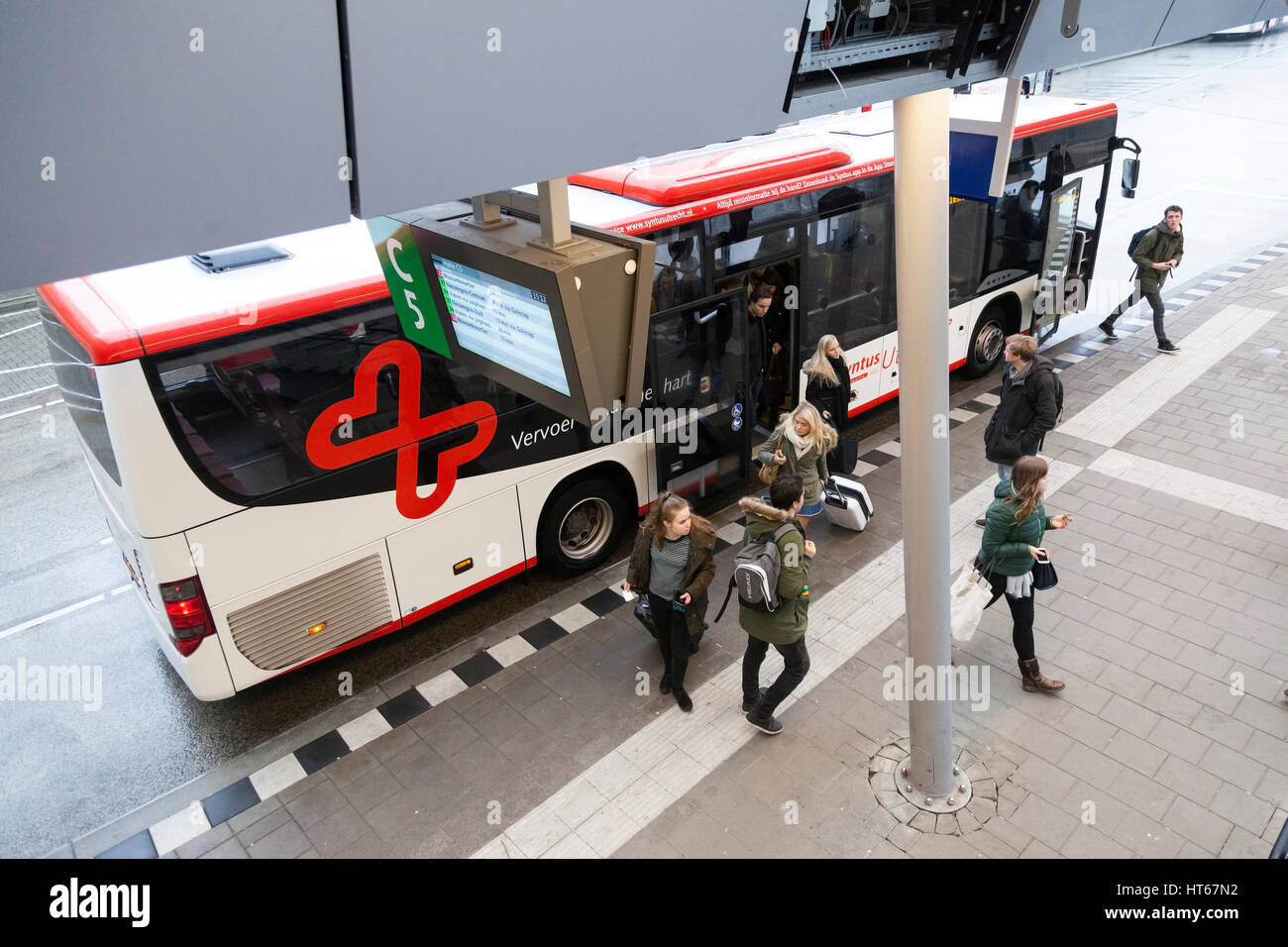 passengers at utrecht station near syntus bus on rainy day in the ...