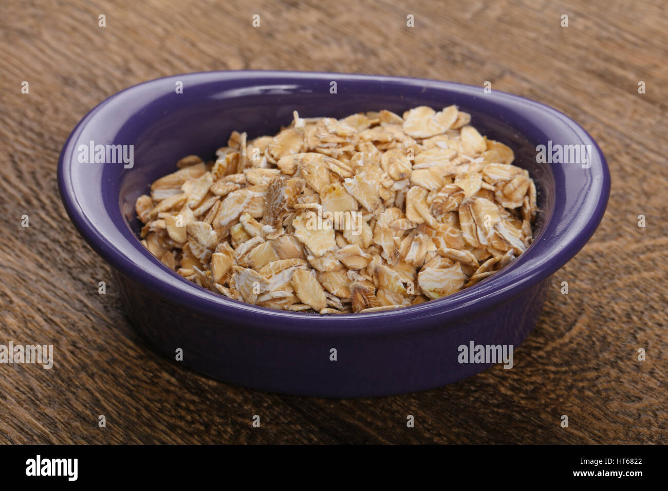 Raw oatmeal heap in the bowl over wooden background Stock Photo - Alamy