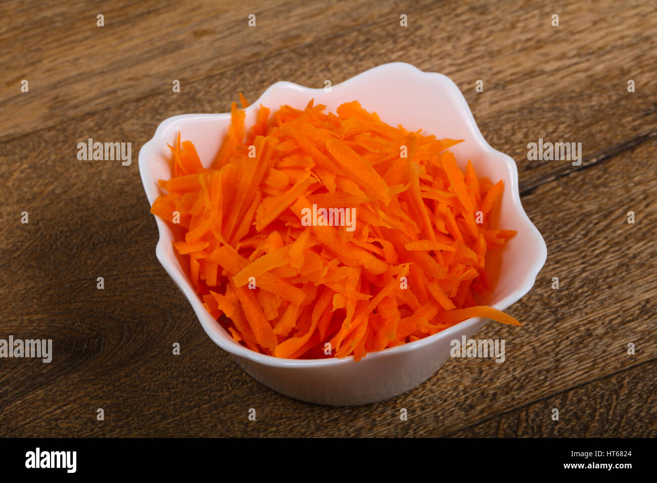 Shredded carrot heap in the bowl over wooden background Stock Photo - Alamy