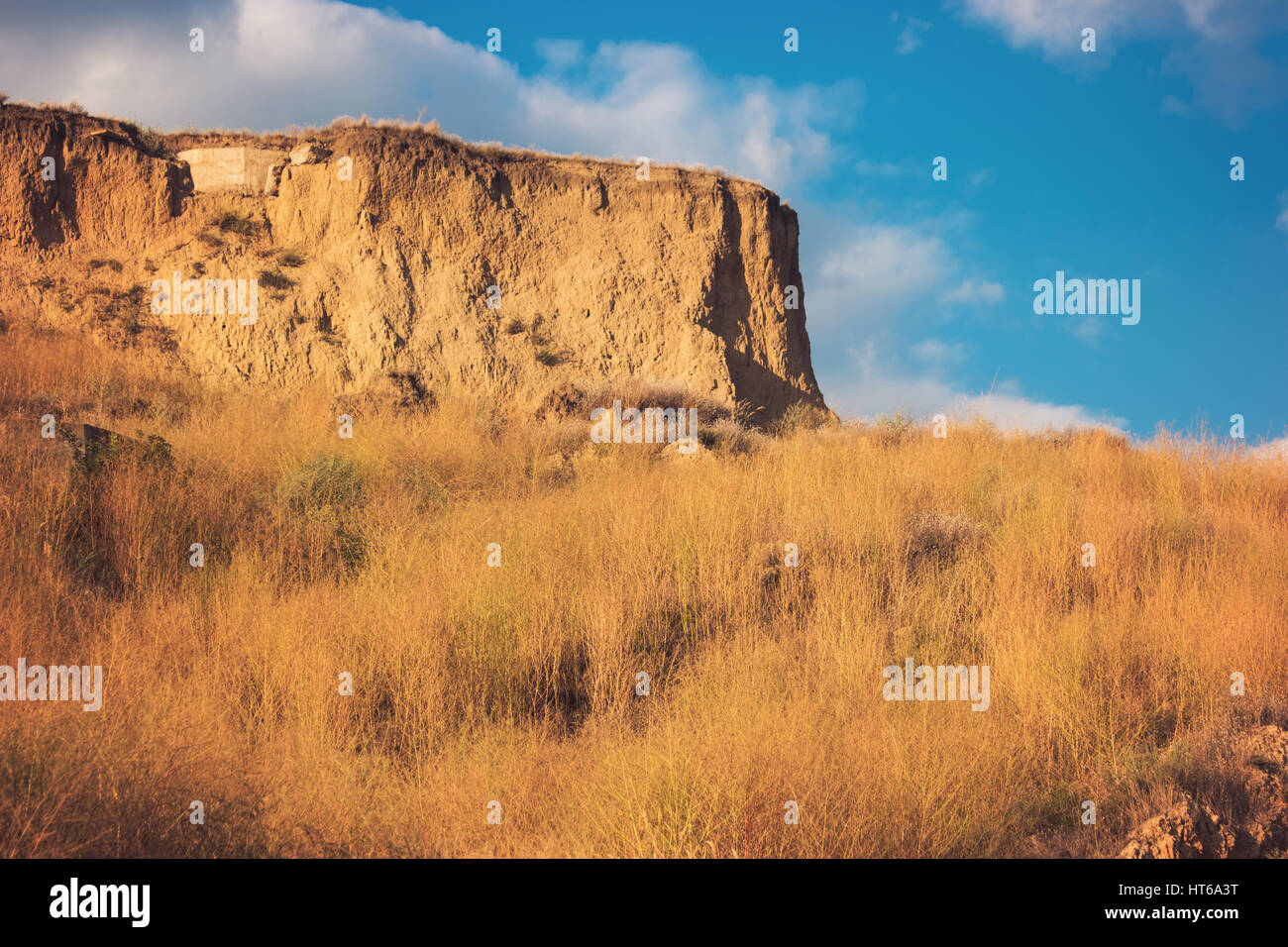 Sky and sandy cliff. Ground and dry grass. Go breathe fresh air. Rest ...