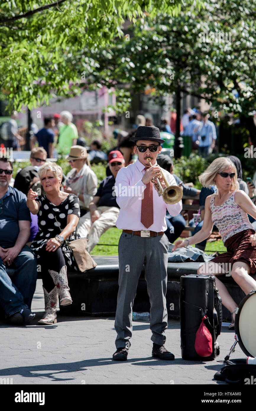 A street musician is playing the trumpet in the middle of a pedestrian ...