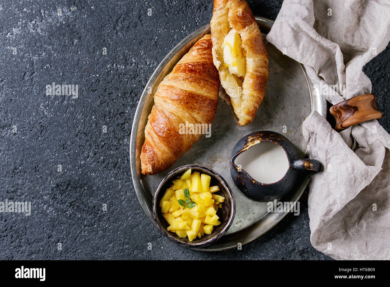 Breakfast with two croissant, butter, cream and sliced mango fruit ...