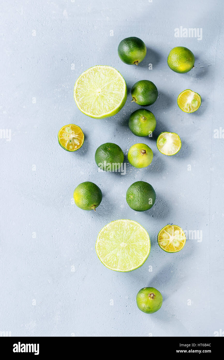 Whole, sliced lime and mini limes over gray stone texture background ...