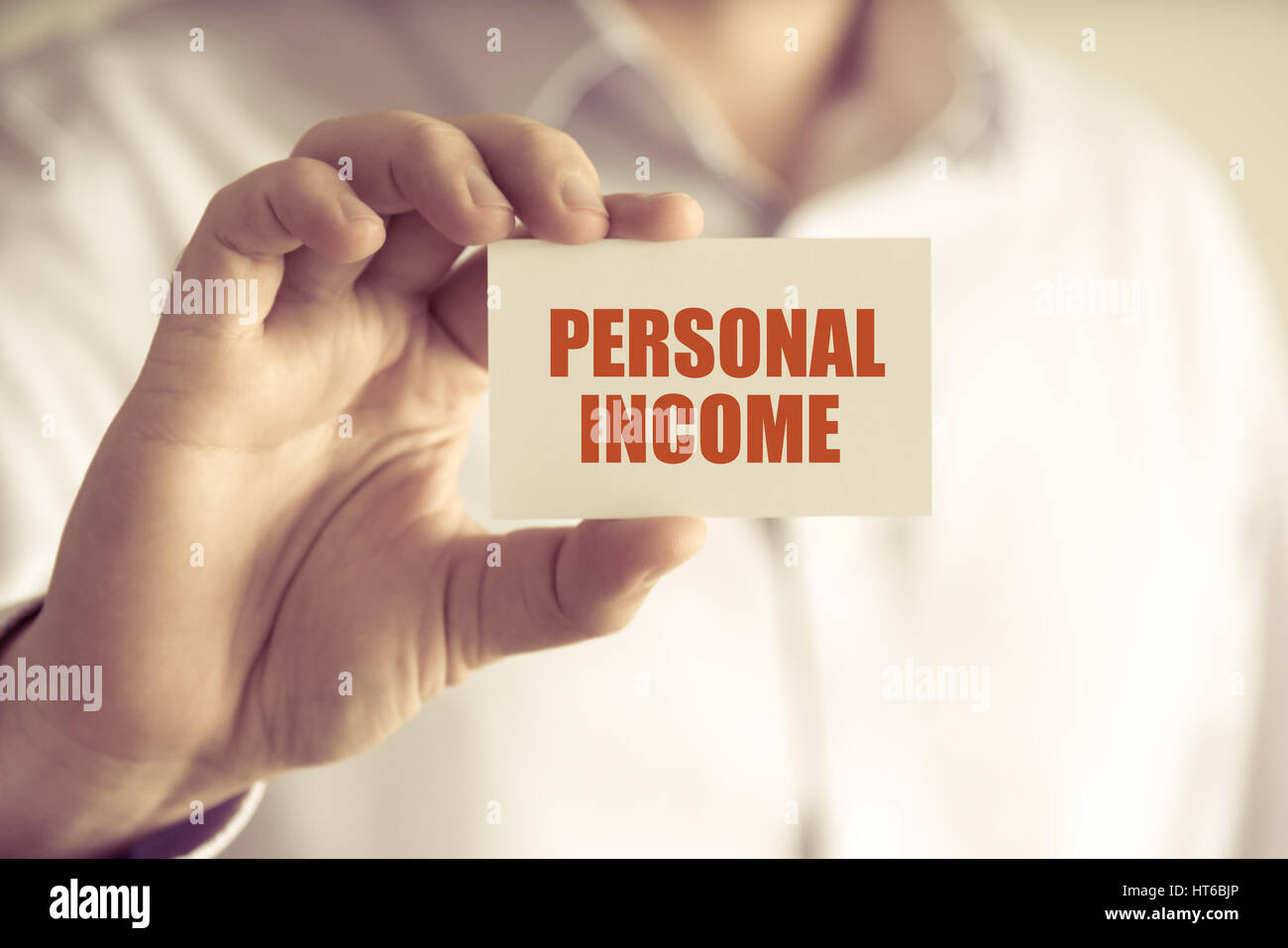 Closeup on businessman holding a card with text PERSONAL INCOME ...