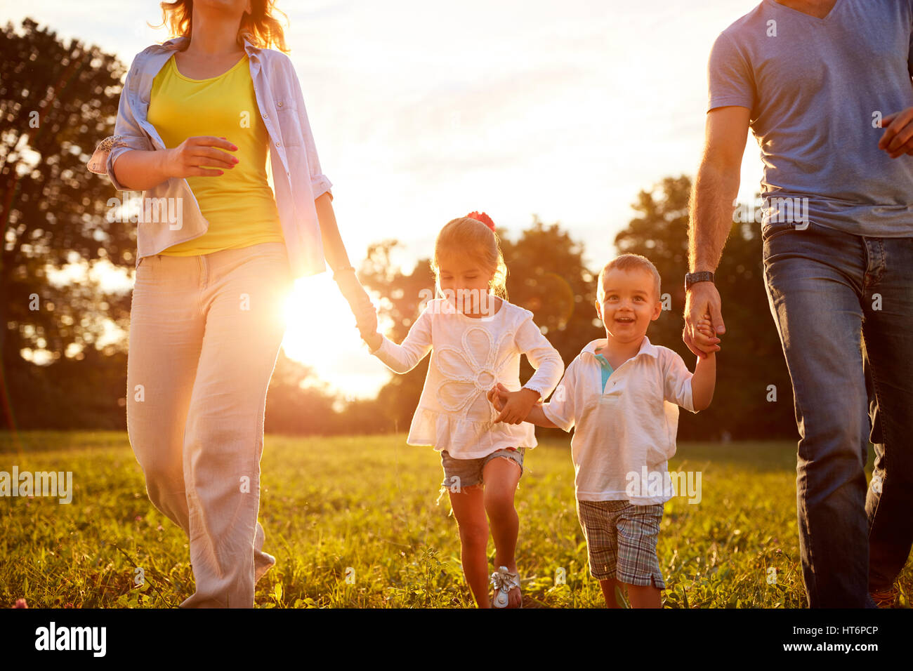 Two young children walking with parents in park Stock Photo - Alamy