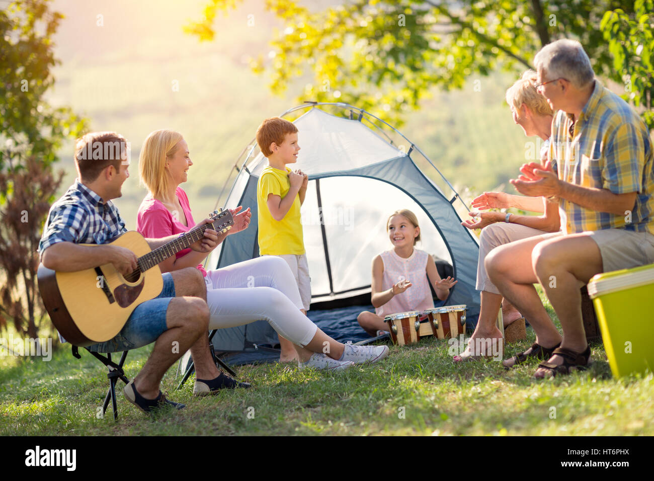family playing a guitar and singing on camping Stock Photo - Alamy