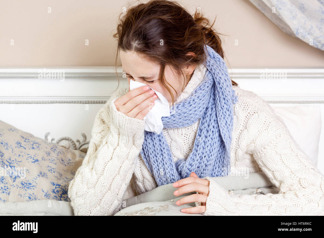 Caught a cold. Closeup image of young sick woman blowing her nose while ...