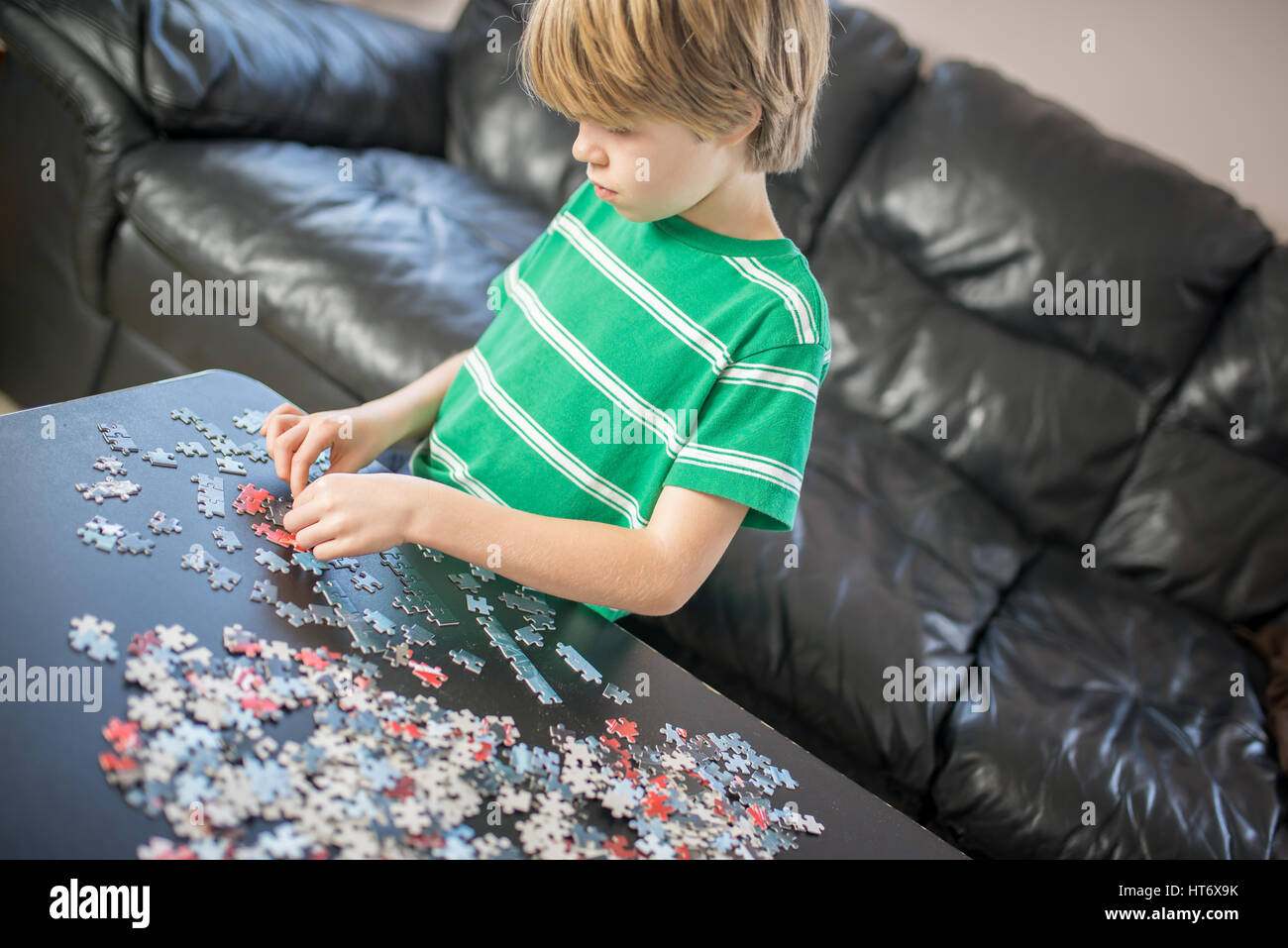 Cute boy doing a puzzle at table Stock Photo - Alamy