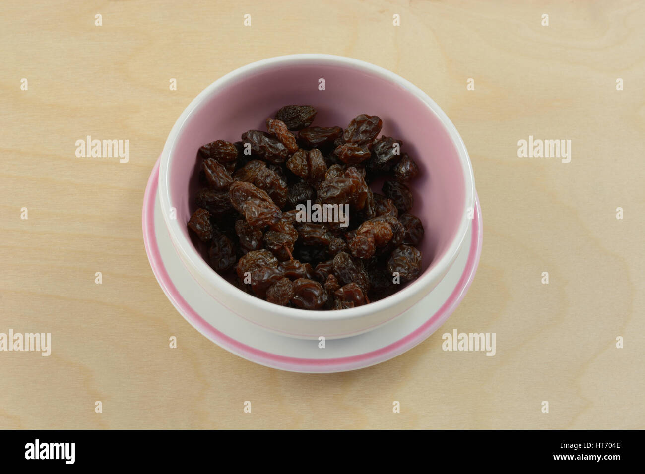 Raisins in small condiment bowl and saucer Stock Photo - Alamy